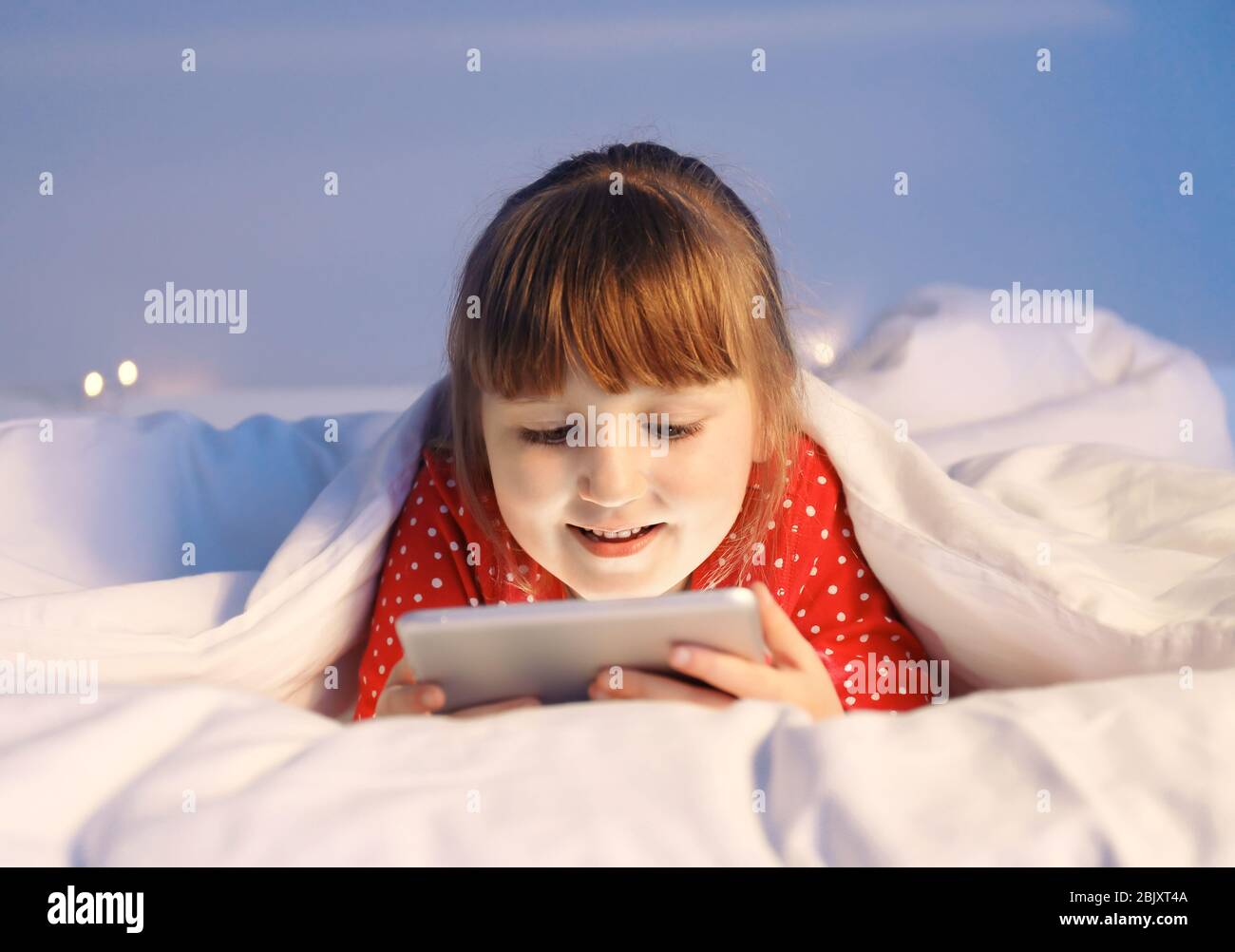 Cute little girl using tablet computer in bed at night Stock Photo - Alamy