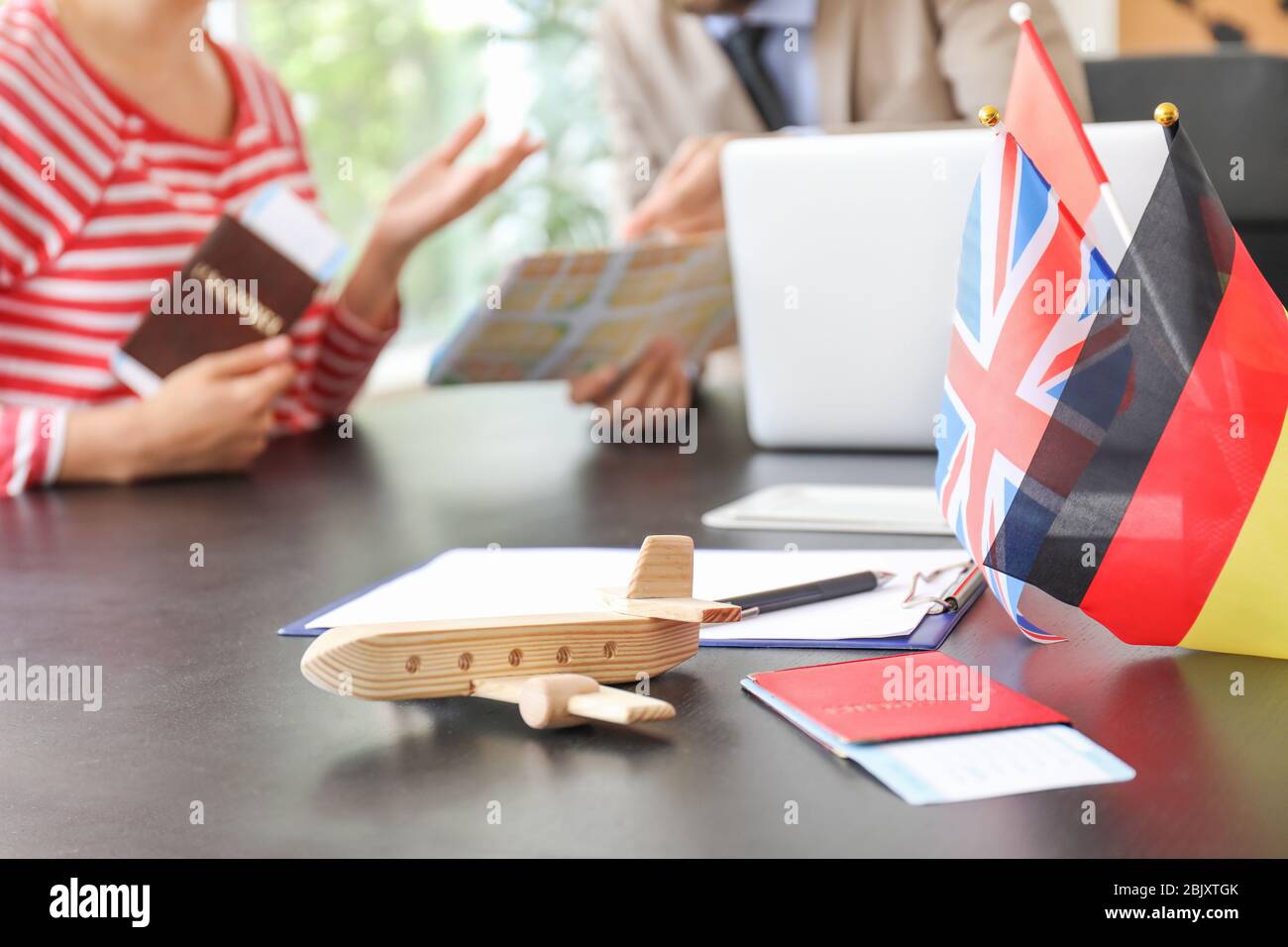 Wooden airplane with passport and ticket on table in travel agency ...