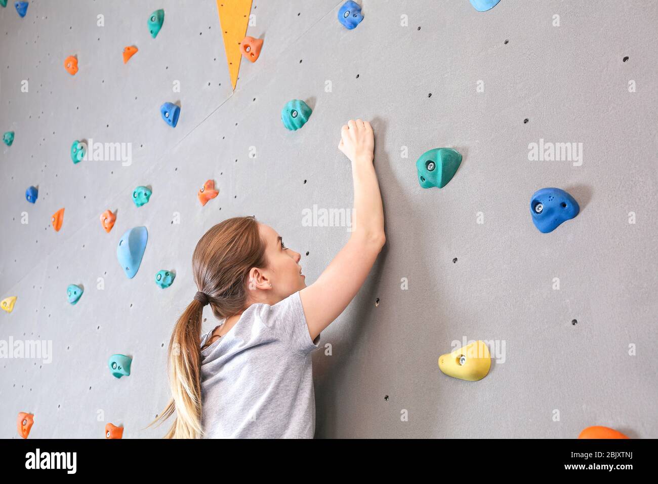 Young woman climbing wall in gym Stock Photo - Alamy