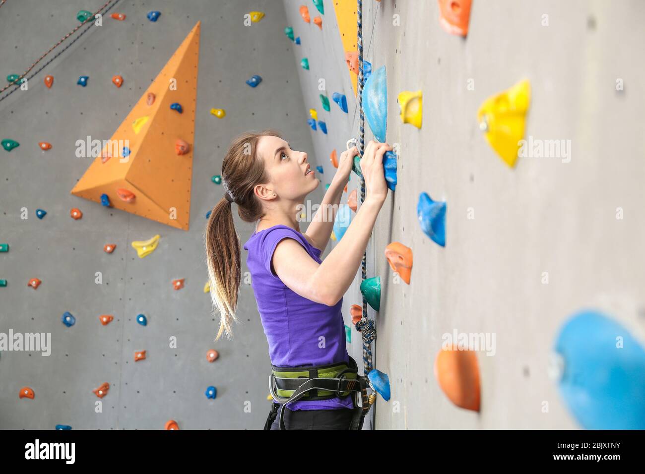 Young woman climbing wall in gym Stock Photo - Alamy