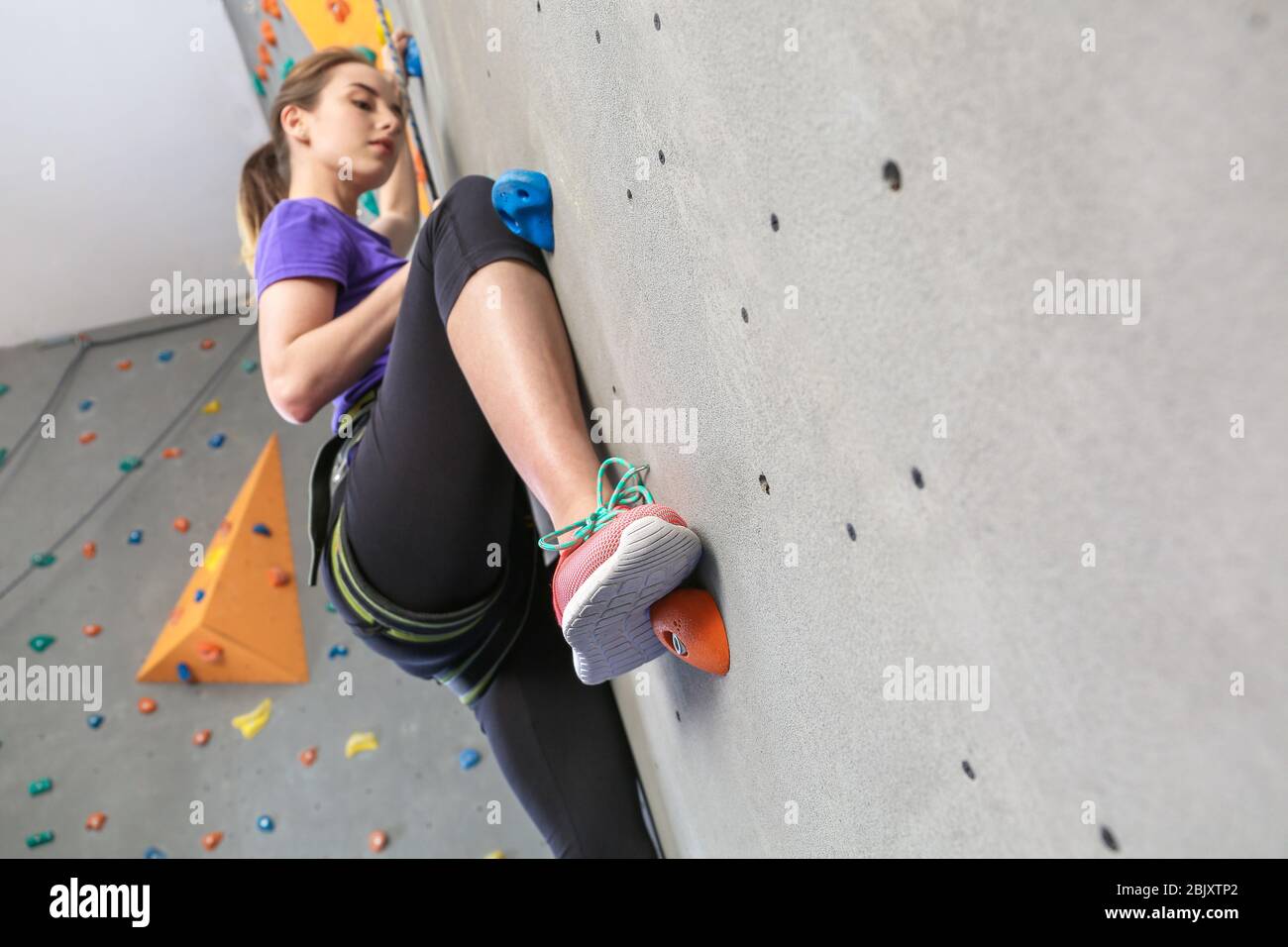 Young woman climbing wall in gym Stock Photo - Alamy