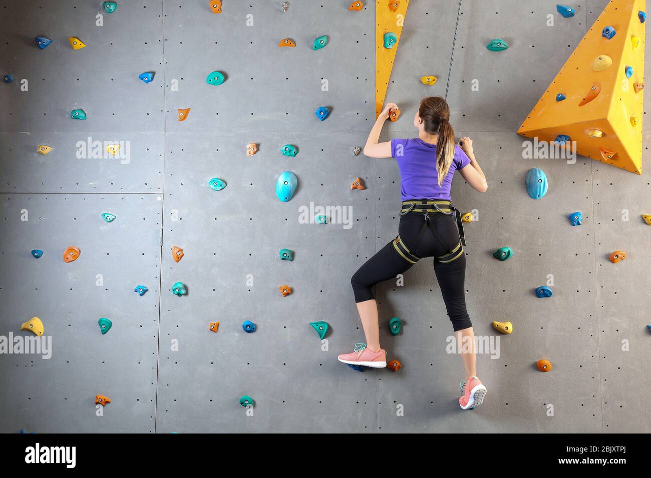 Young woman climbing wall in gym Stock Photo - Alamy