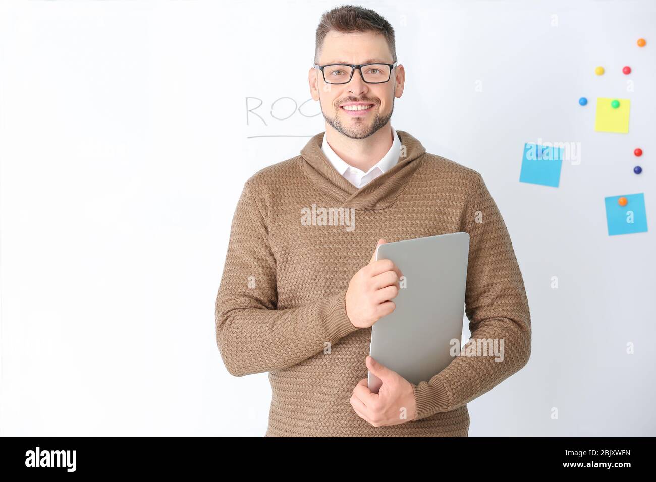 Handsome male teacher with laptop near blackboard in classroom Stock ...