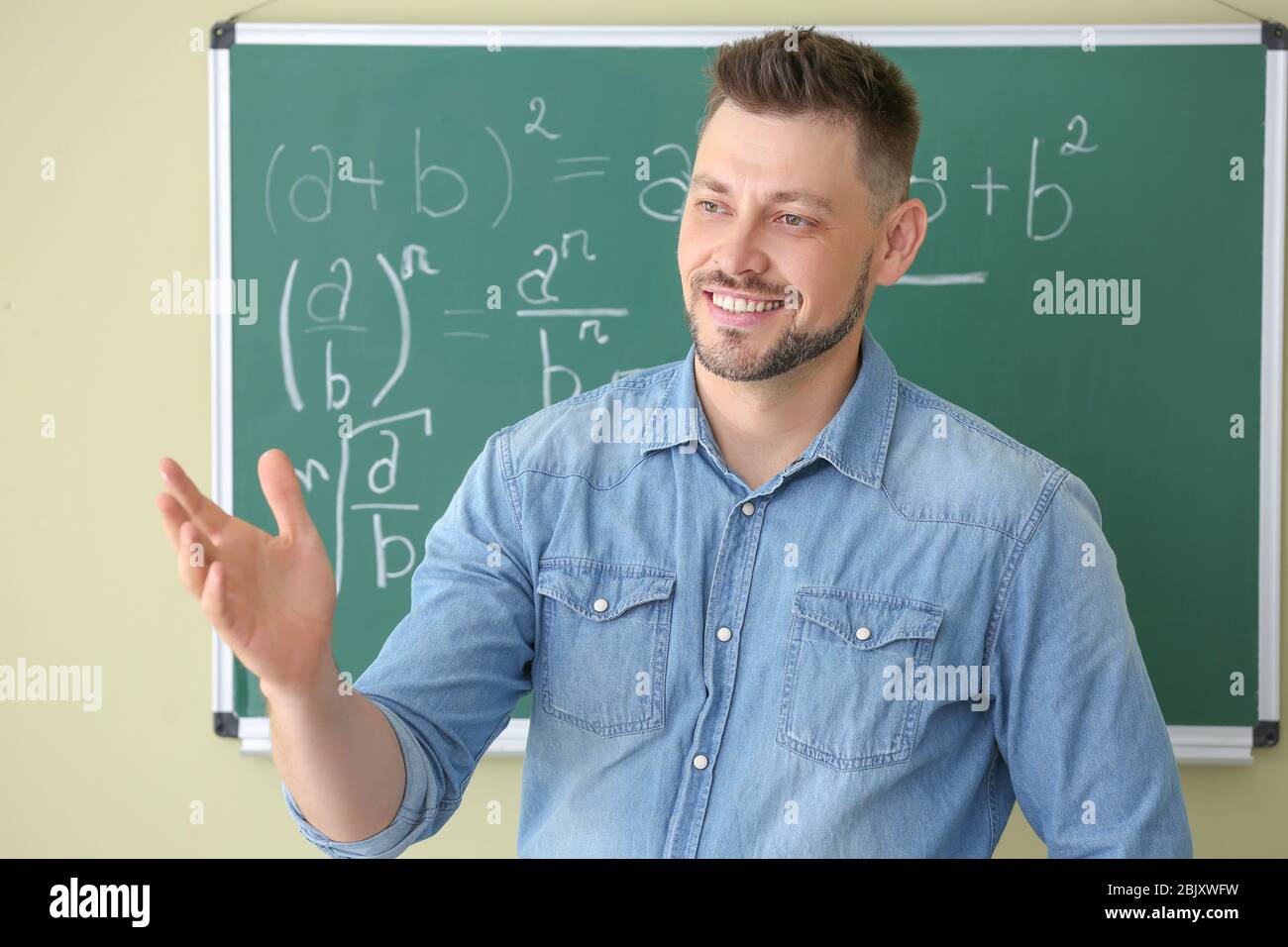 Handsome math teacher near blackboard in classroom Stock Photo - Alamy