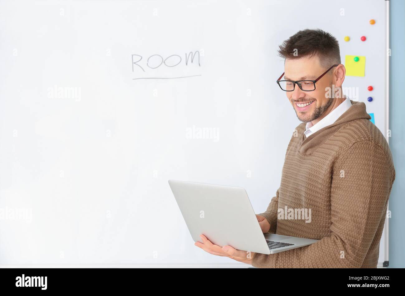 Handsome male teacher with laptop near blackboard in classroom Stock ...