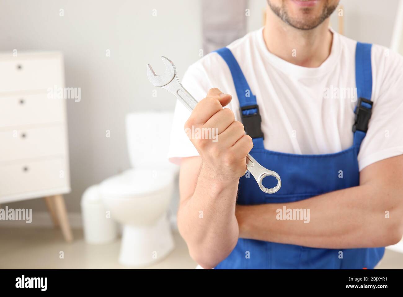 Plumber with wrench in restroom Stock Photo - Alamy