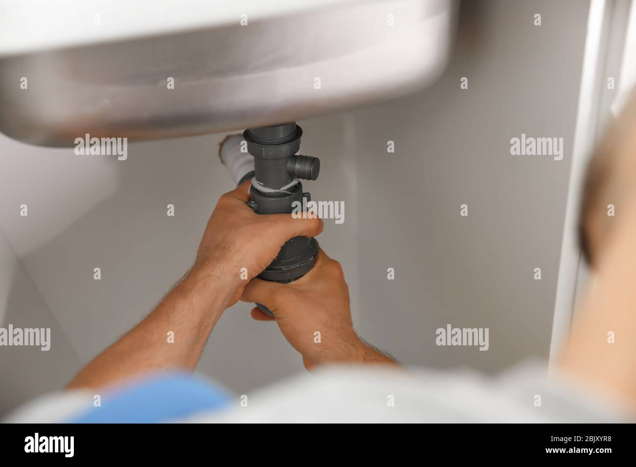 Plumber installing sink in kitchen Stock Photo - Alamy