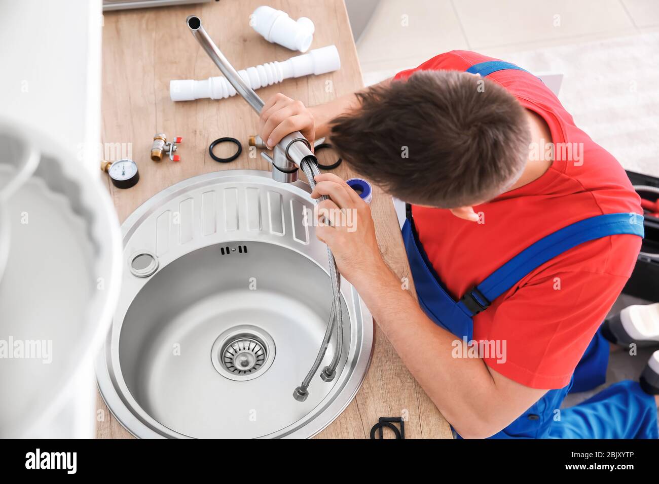 Plumber installing sink in kitchen Stock Photo - Alamy