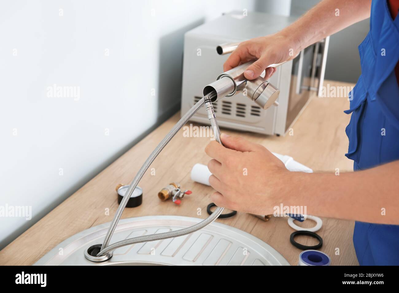 Plumber installing sink in kitchen Stock Photo - Alamy