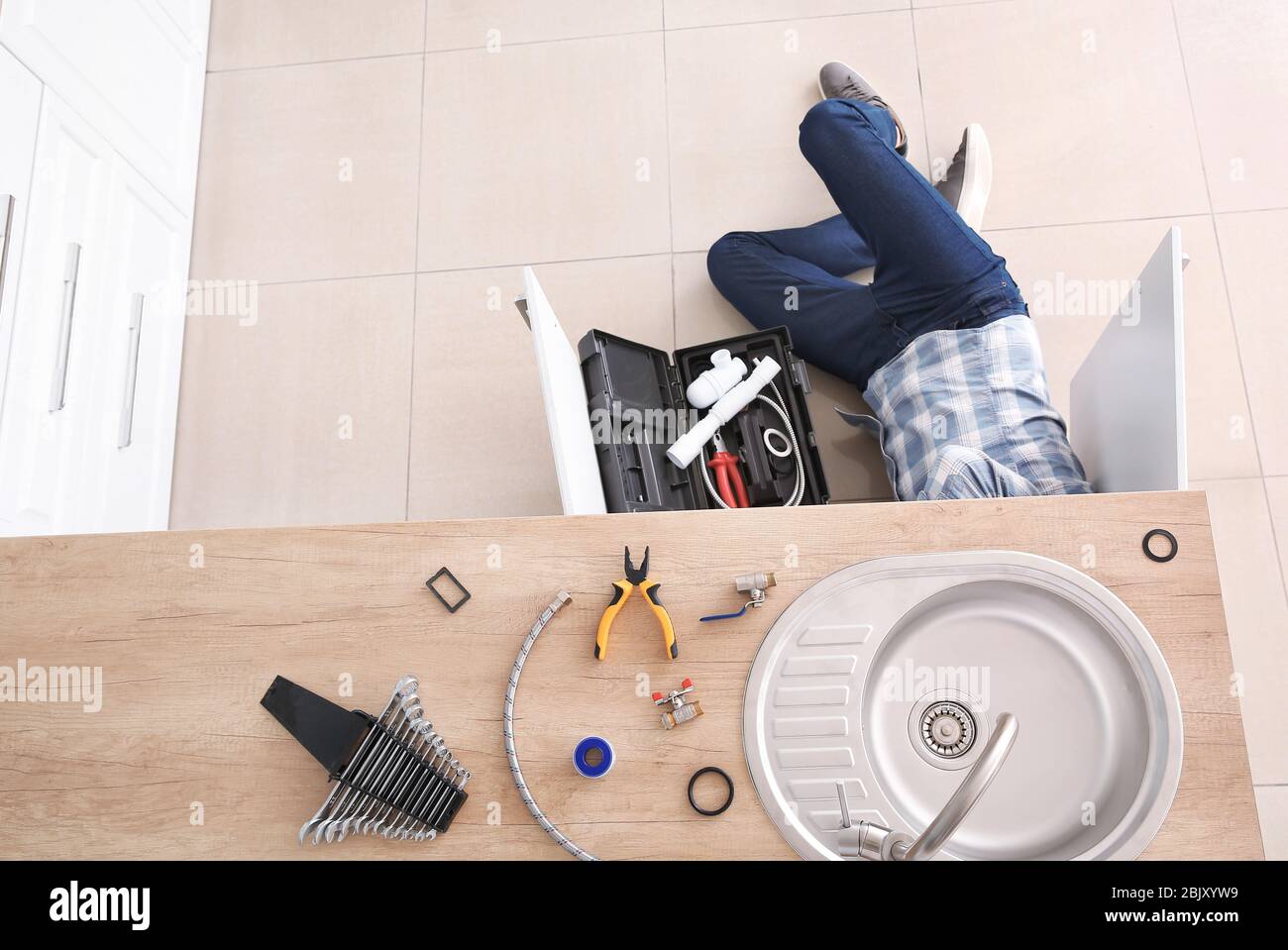 Plumber installing sink in kitchen Stock Photo - Alamy