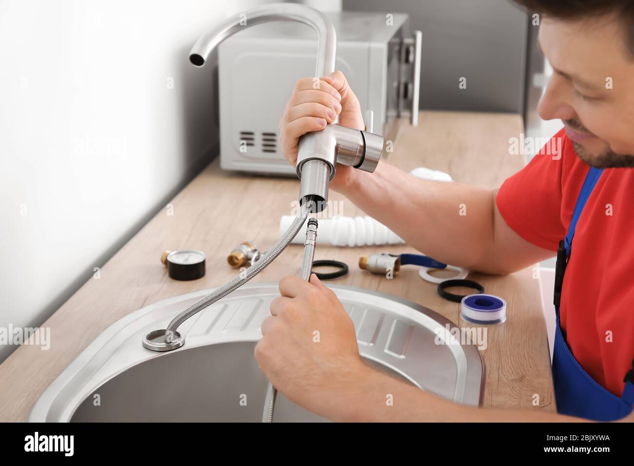 Plumber installing sink in kitchen Stock Photo - Alamy
