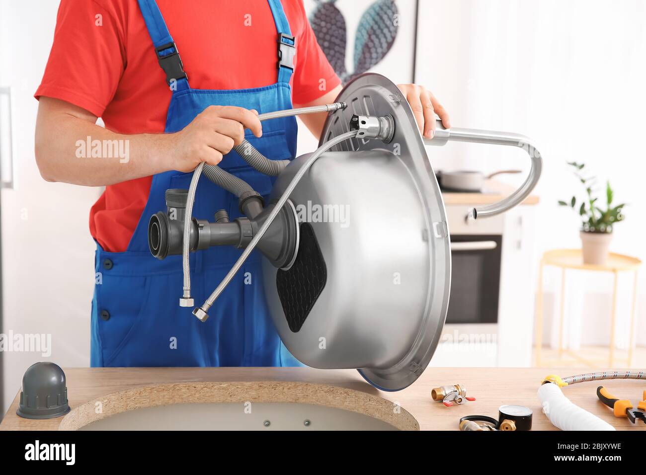 Plumber installing sink in kitchen Stock Photo - Alamy