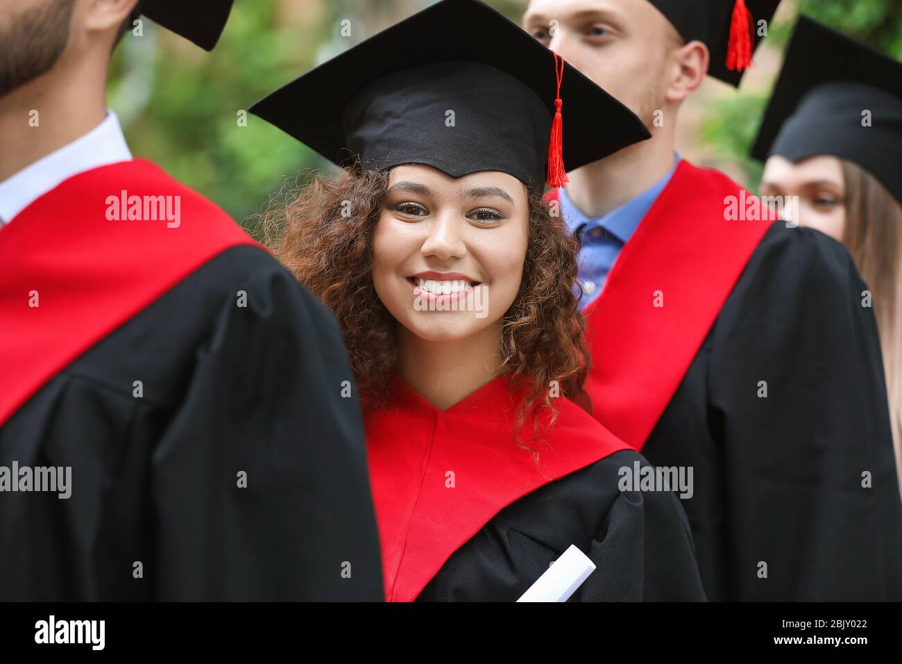 Happy students in bachelor robes outdoors Stock Photo - Alamy