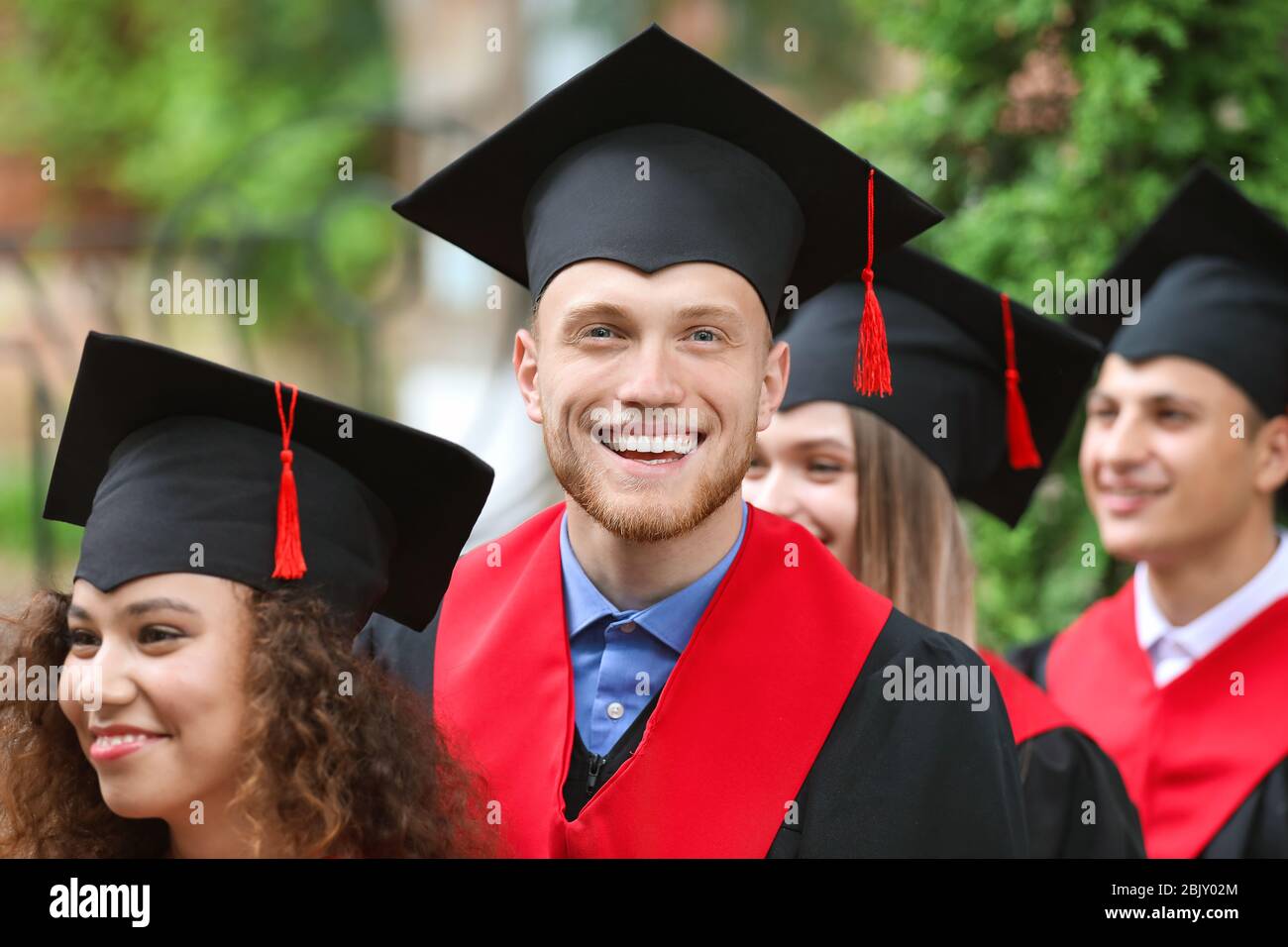 Happy students in bachelor robes outdoors Stock Photo - Alamy