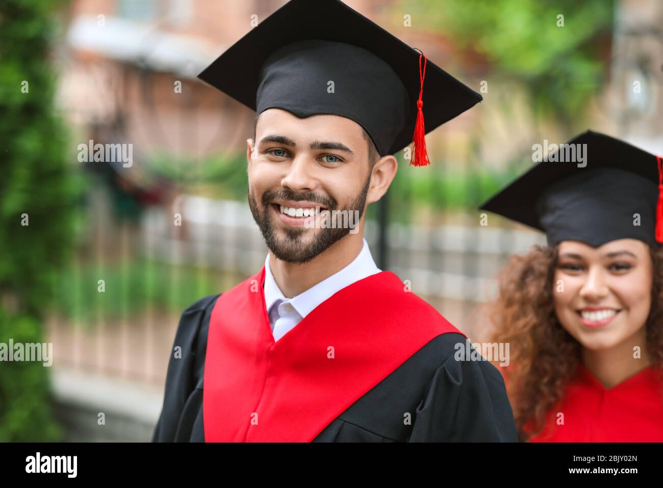 Happy students in bachelor robes outdoors Stock Photo - Alamy