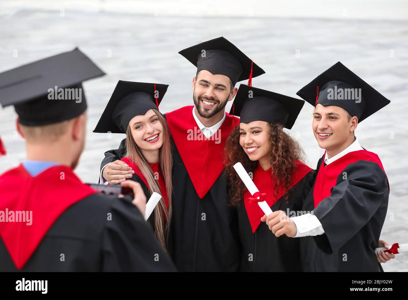 Happy students in bachelor robes and with diplomas outdoors Stock Photo ...