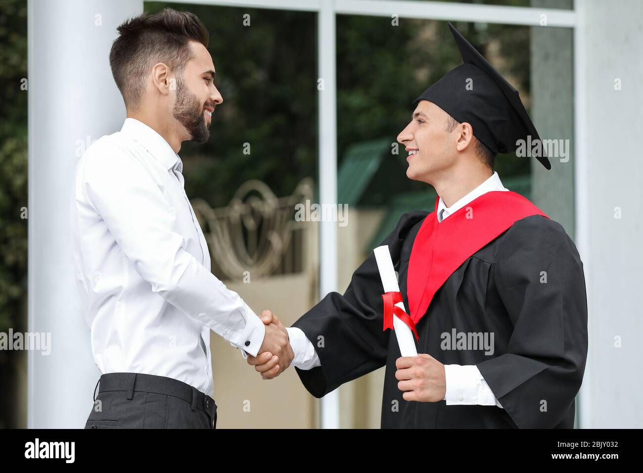 Professor greeting young student on his graduation day Stock Photo - Alamy
