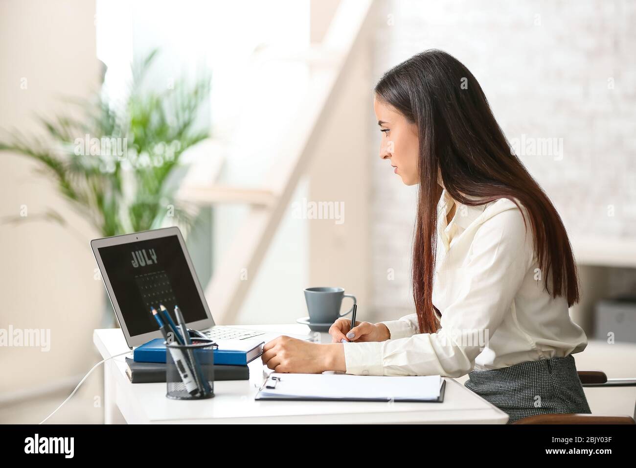 Woman using calendar on laptop screen while working in office Stock ...