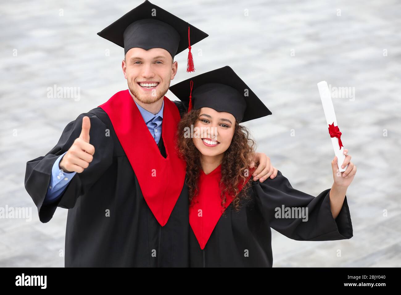 Happy students in bachelor robes outdoors Stock Photo - Alamy