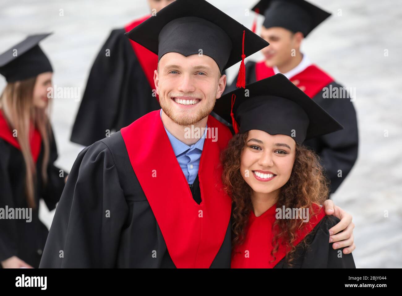 Happy students in bachelor robes outdoors Stock Photo - Alamy