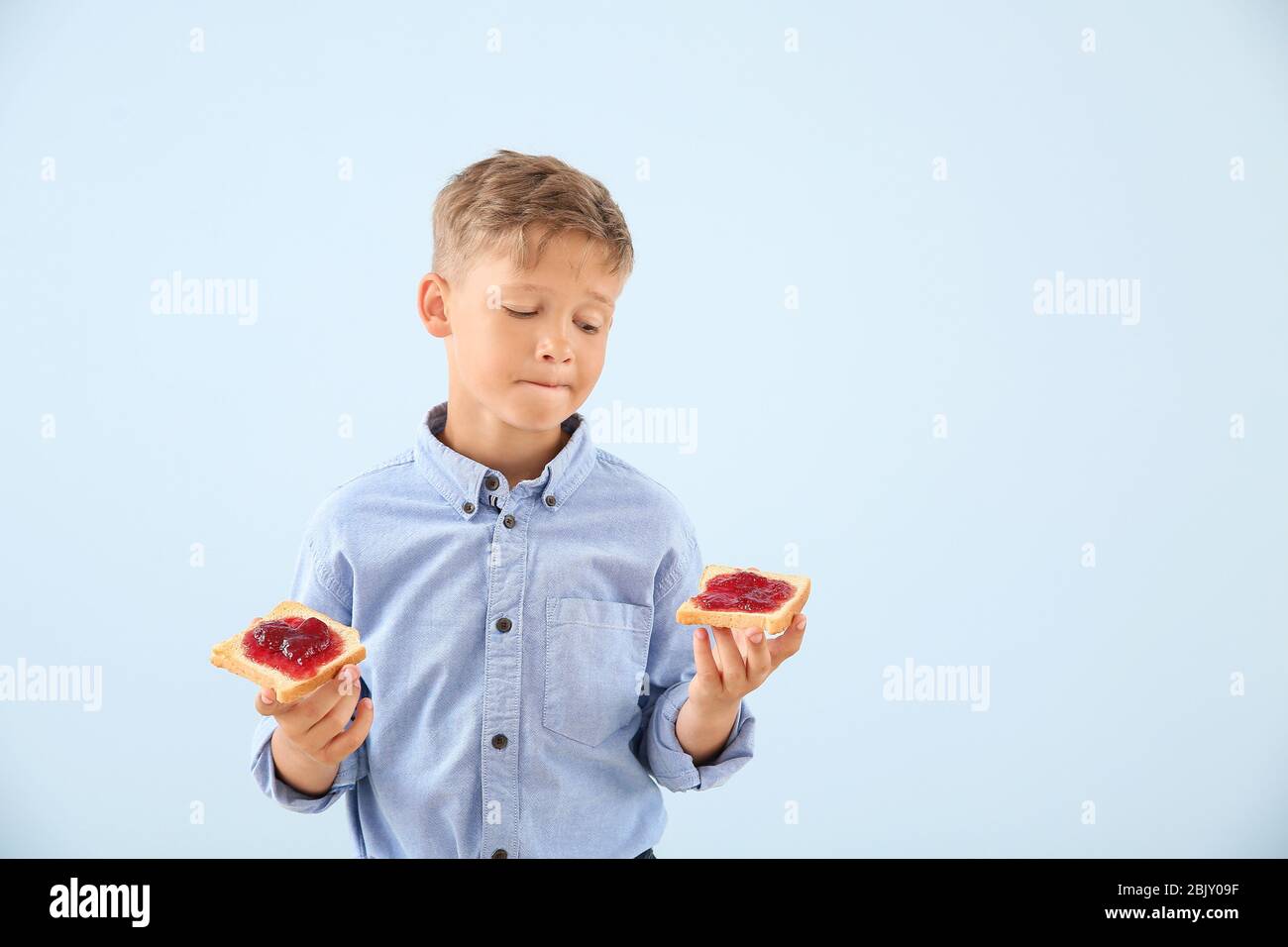 Funny little boy choosing between toast with jam and toast with ...