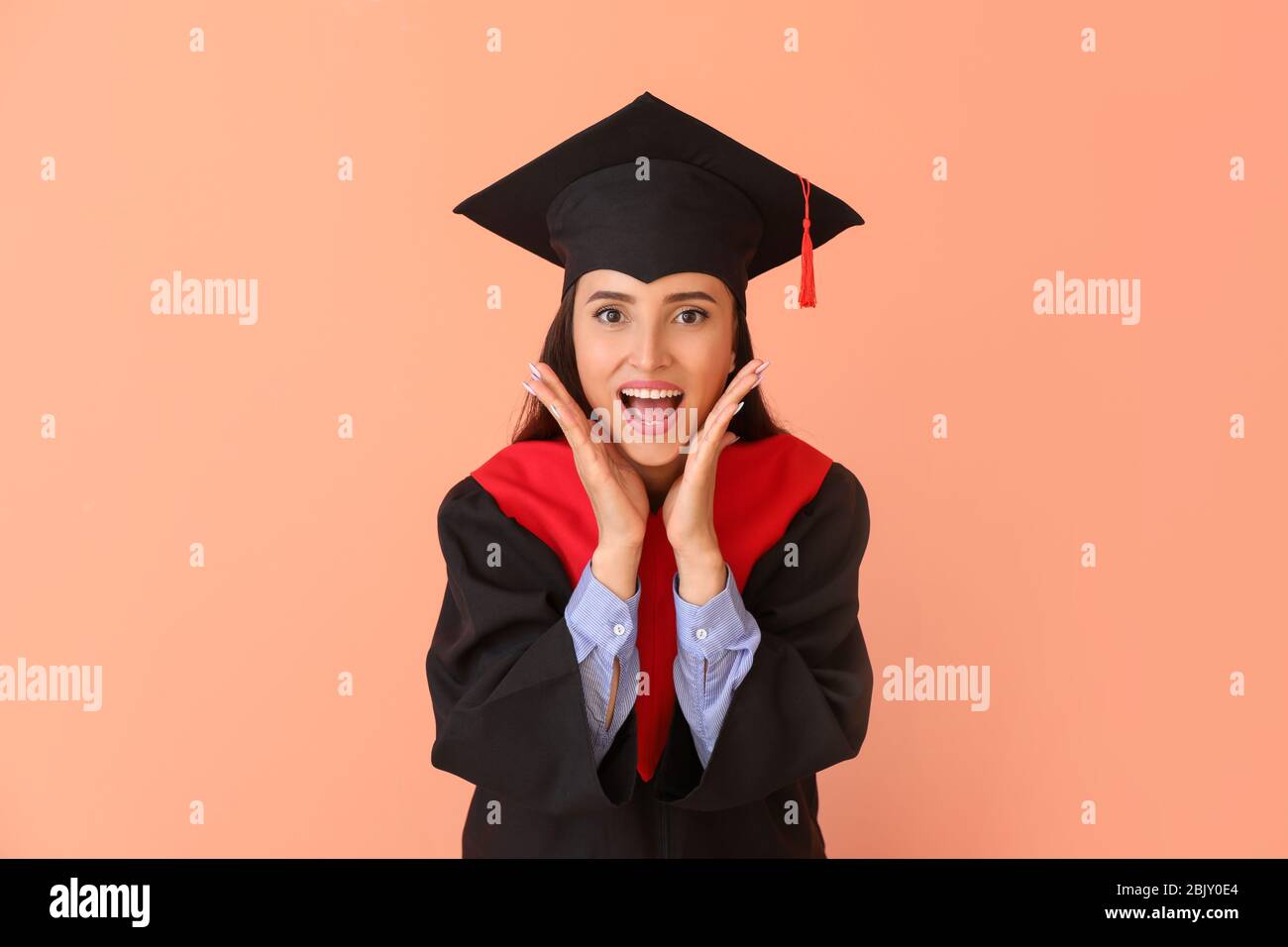 Surprised female graduate on color background Stock Photo - Alamy