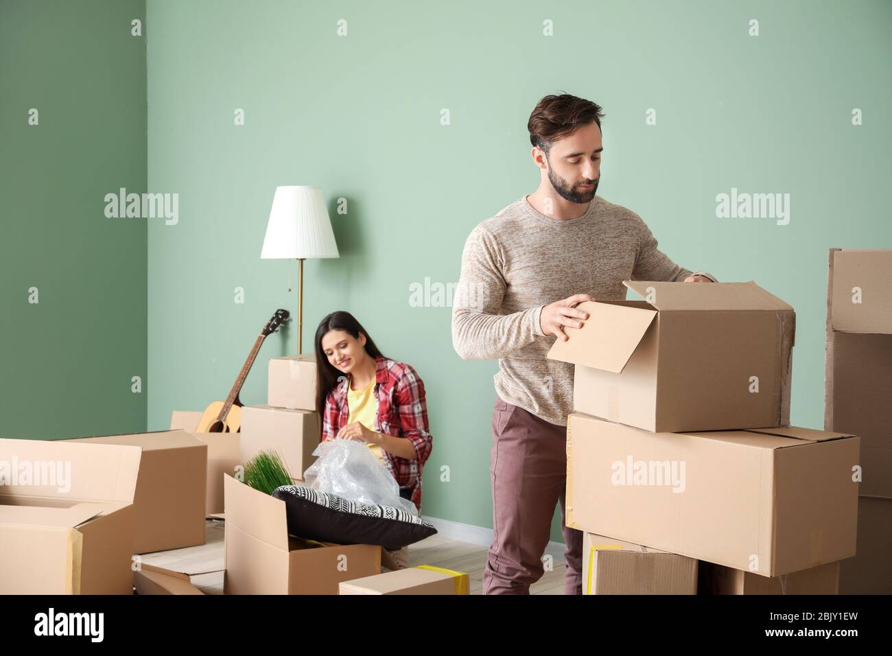 Young couple unpacking things after moving into new house Stock Photo ...