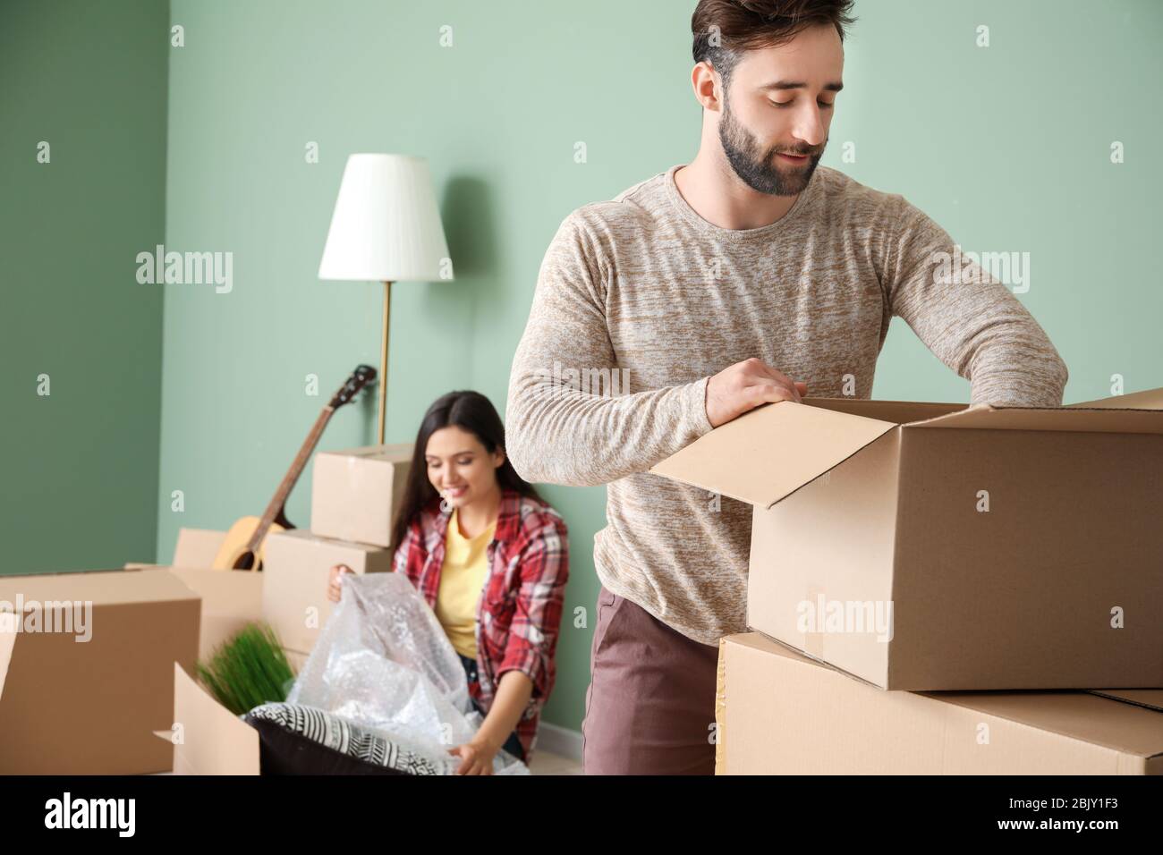 Young couple unpacking things after moving into new house Stock Photo ...