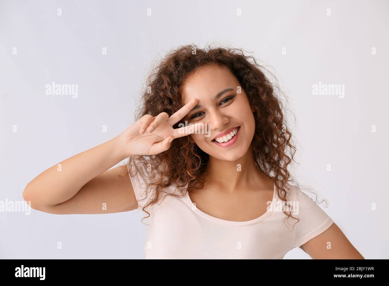 Beautiful African-American woman showing victory gesture on white ...