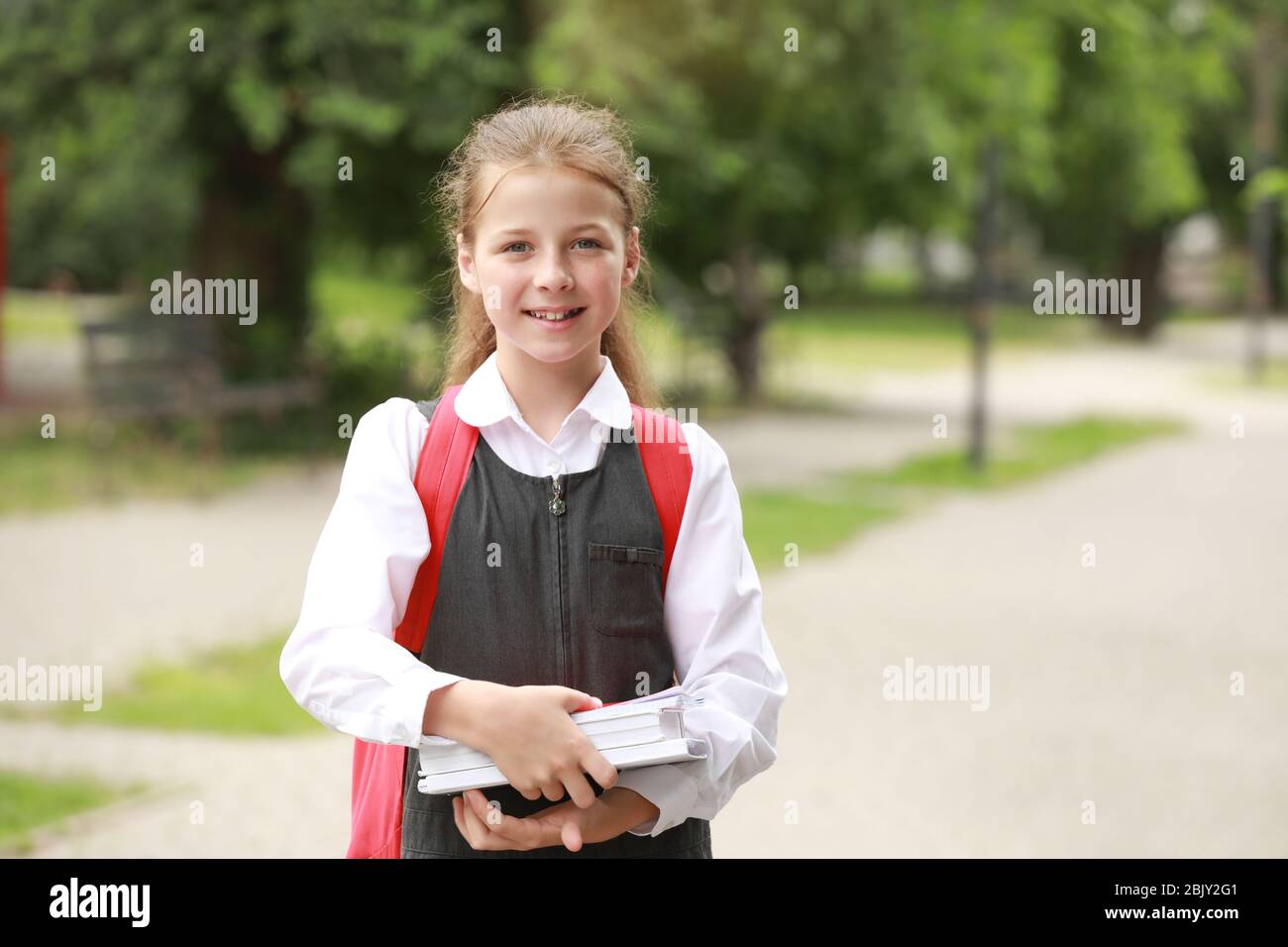 Cute little schoolgirl in park Stock Photo - Alamy