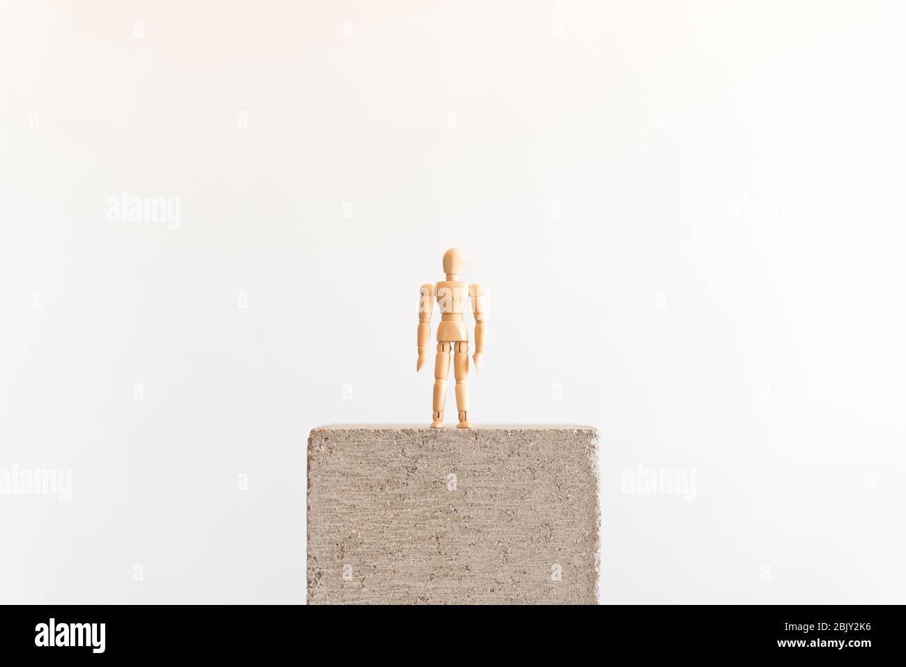 Wooden human figure standing isolated on a concrete block. Symbol of ...