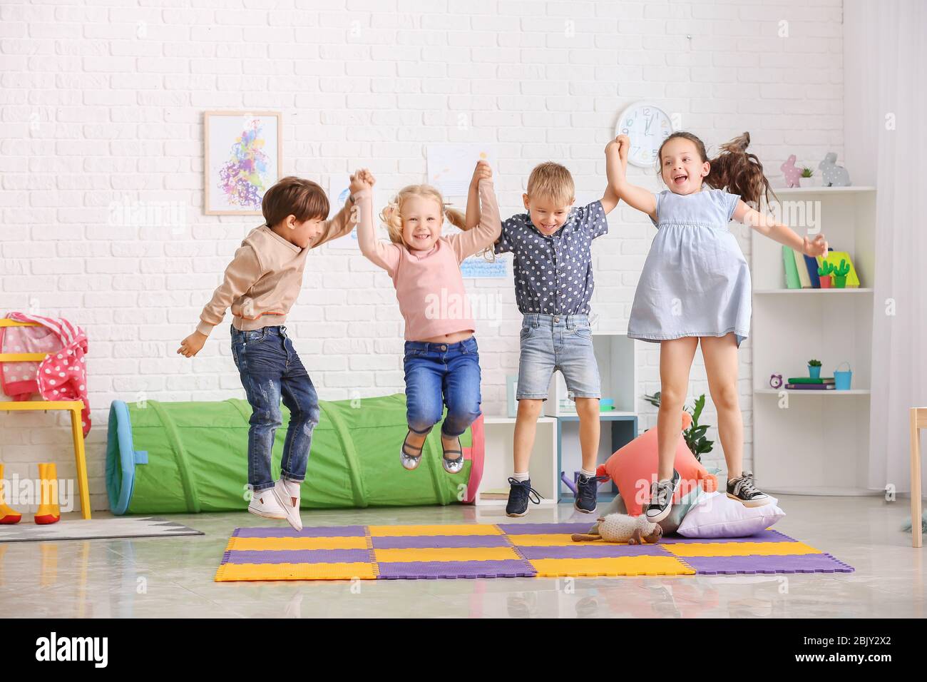 Jumping little children in kindergarten Stock Photo - Alamy