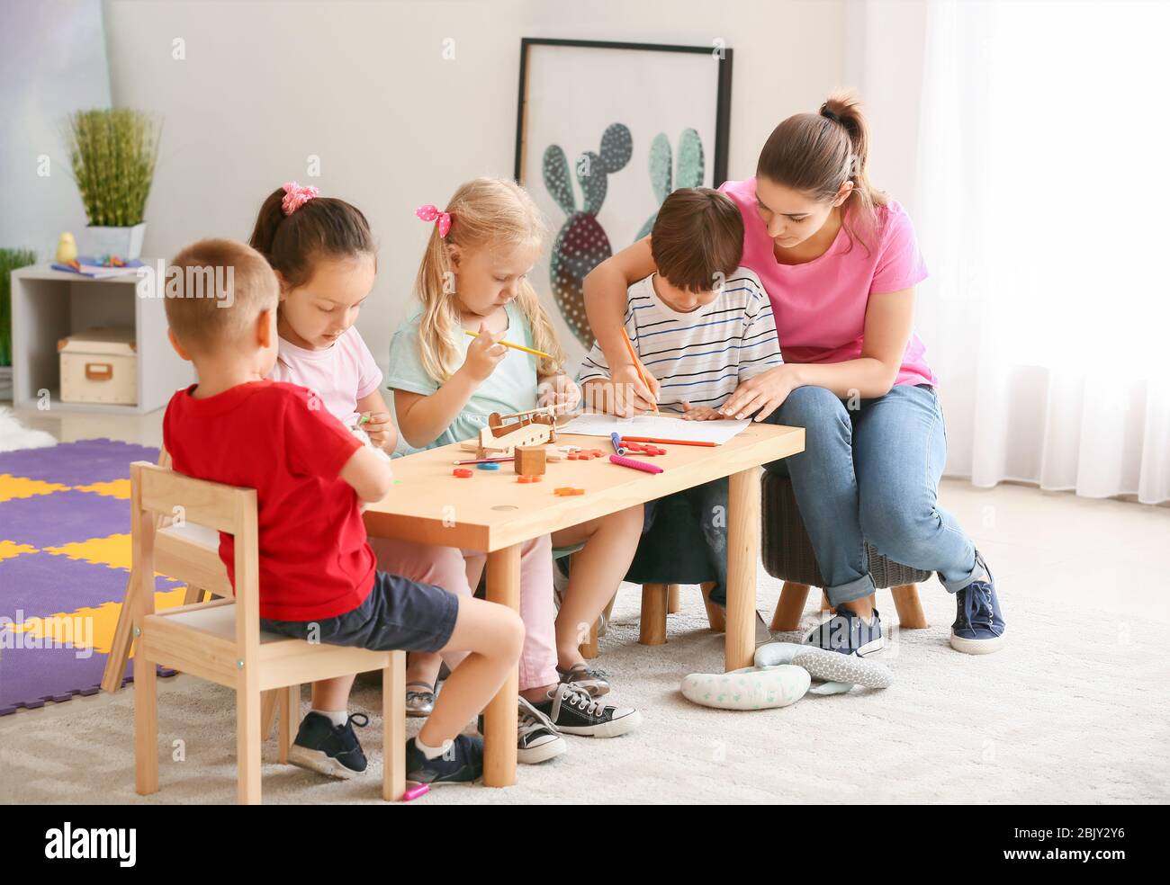 Nursery teacher with cute little children in kindergarten Stock Photo ...