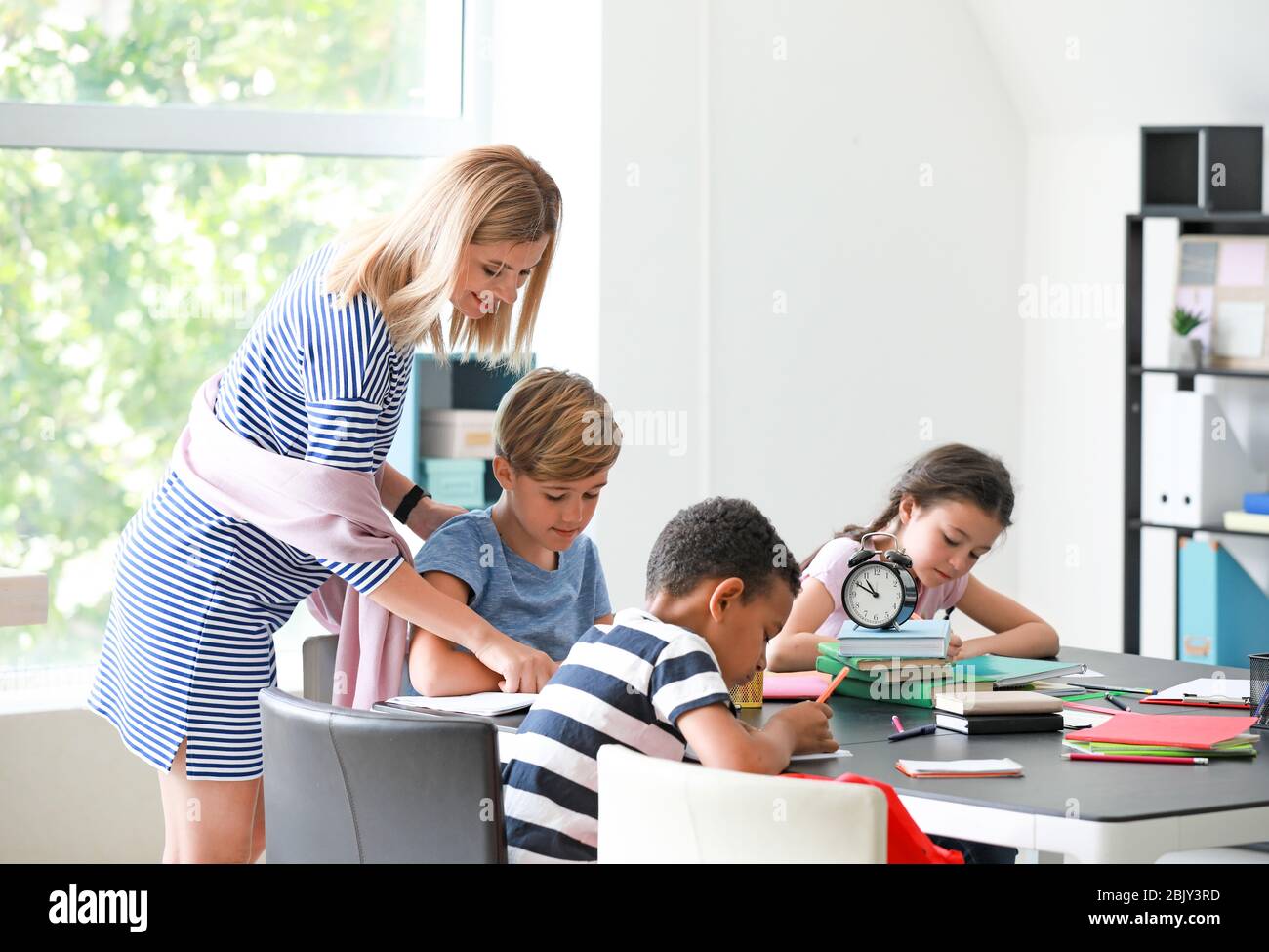 Cute children with teacher during lesson in classroom Stock Photo - Alamy