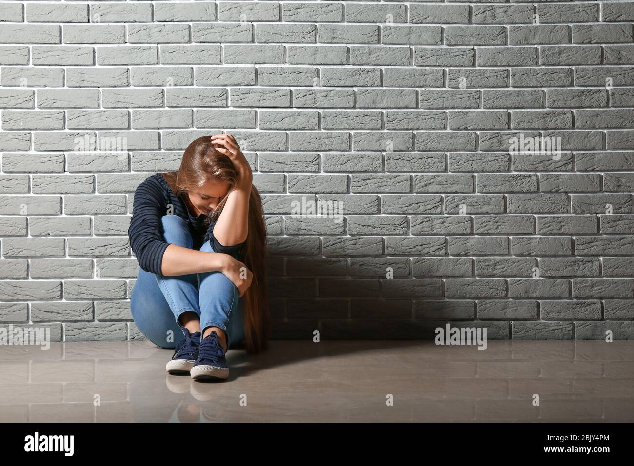 Woman having panic attack while sitting near brick wall Stock Photo - Alamy