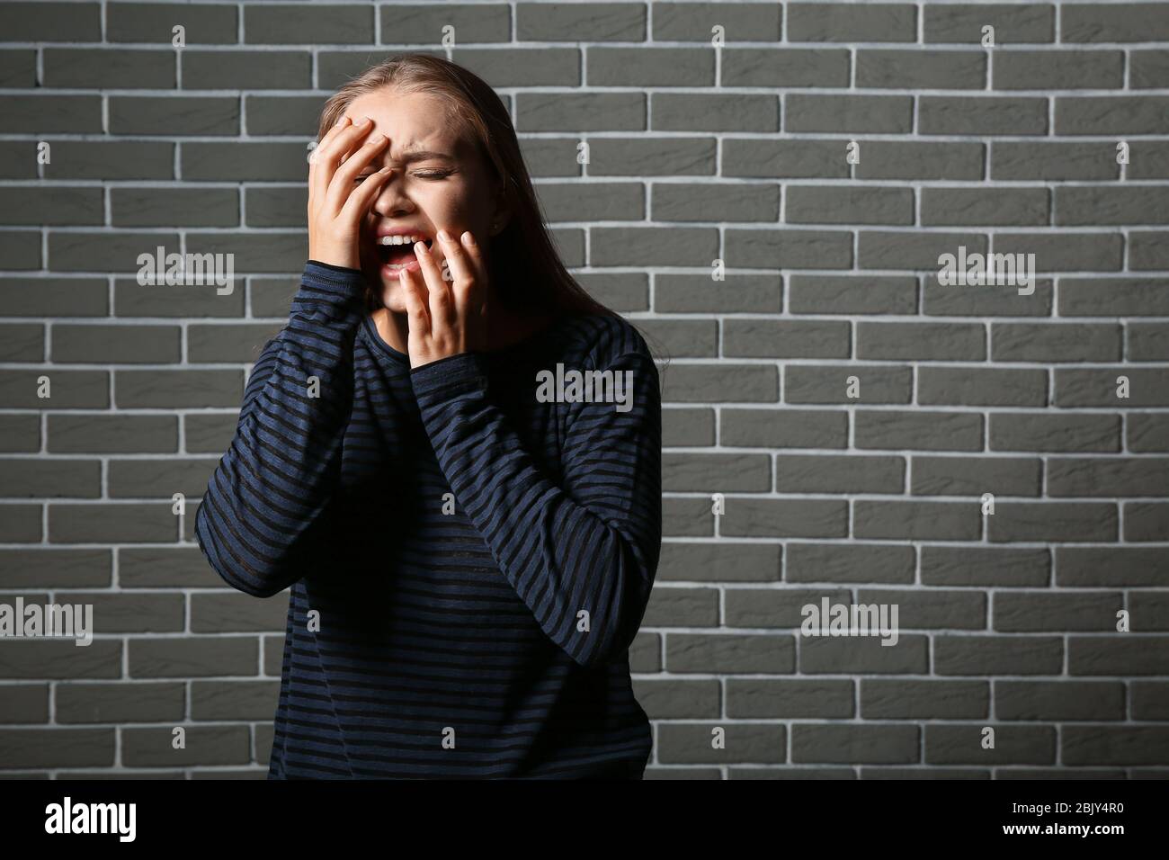 Woman having panic attack against brick wall Stock Photo - Alamy