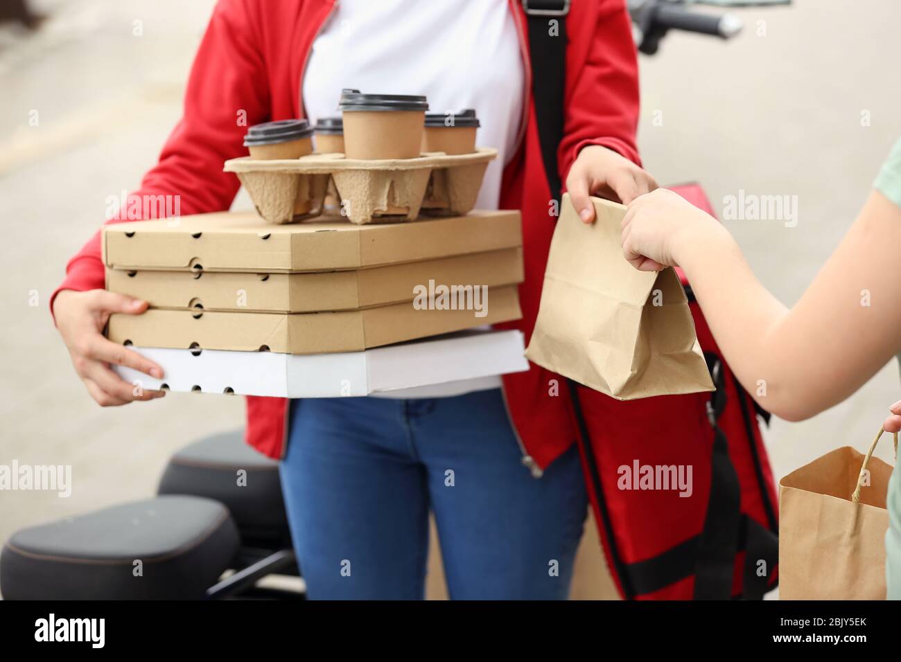 Woman taking order from courier of food delivery service outdoors Stock ...