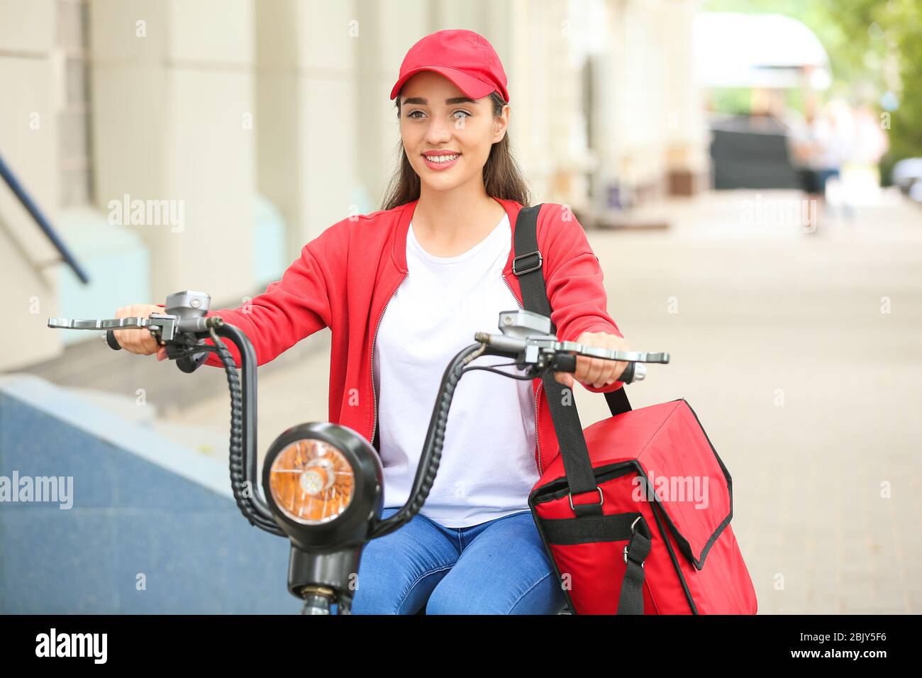 Female worker of food delivery service riding scooter outdoors Stock ...