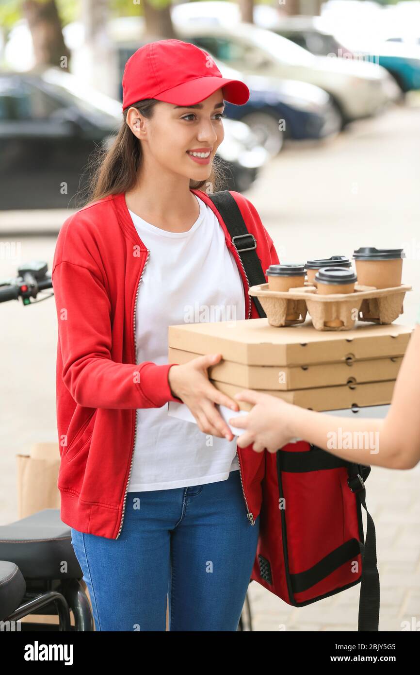 Woman taking order from courier of food delivery service outdoors Stock ...