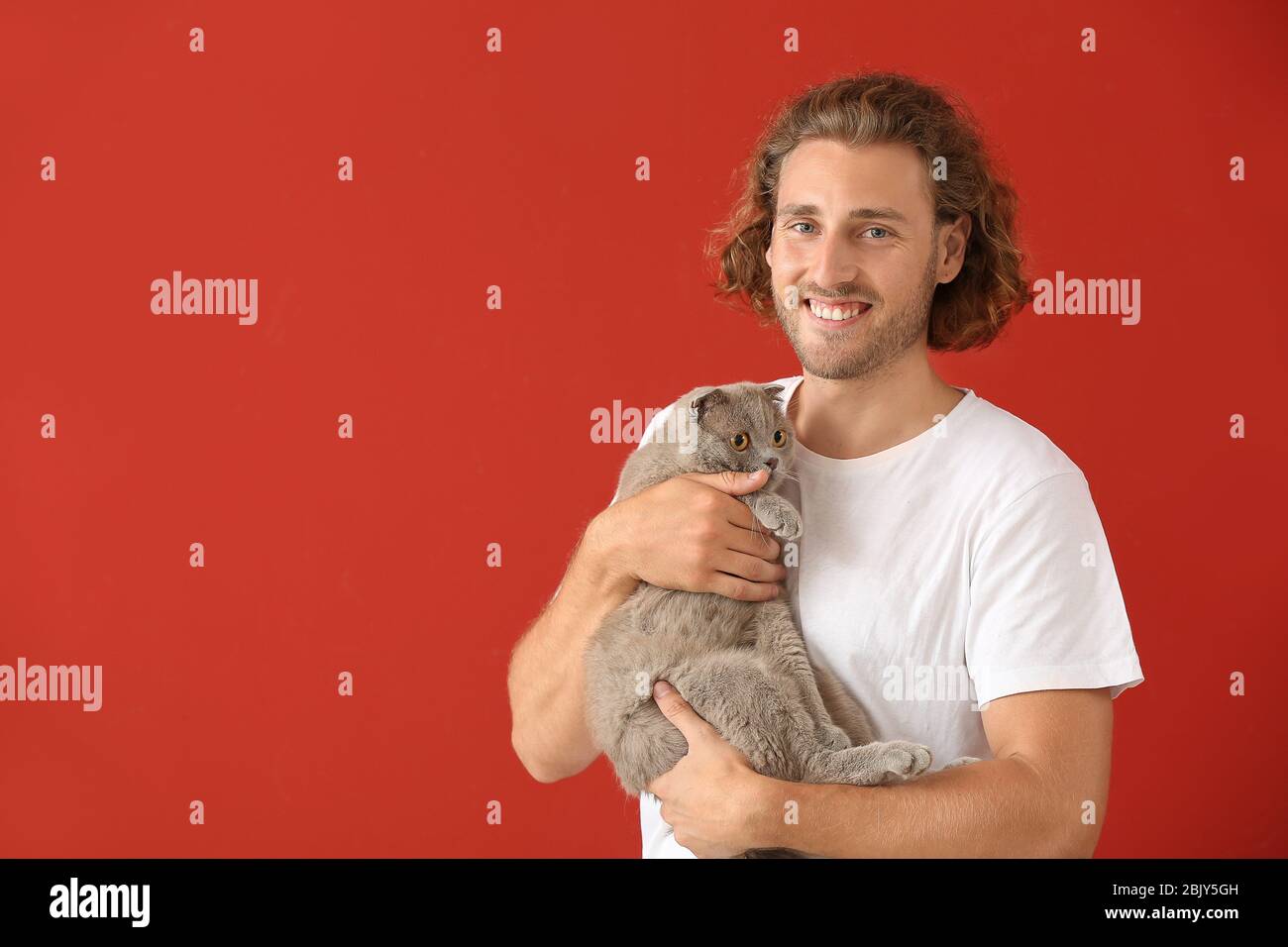 Man with cute funny cat on color background Stock Photo - Alamy