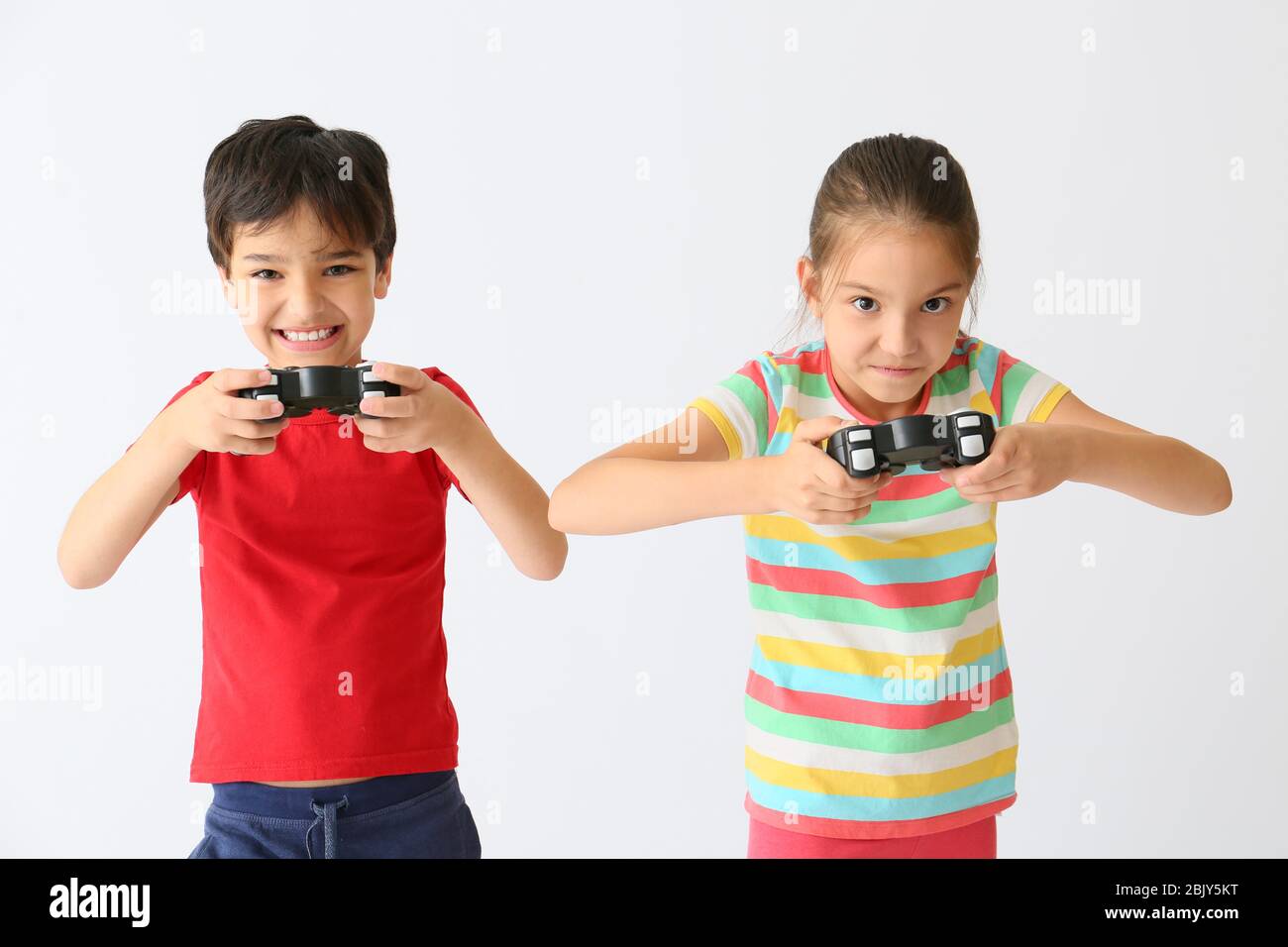 Emotional children playing video games on light background Stock Photo ...