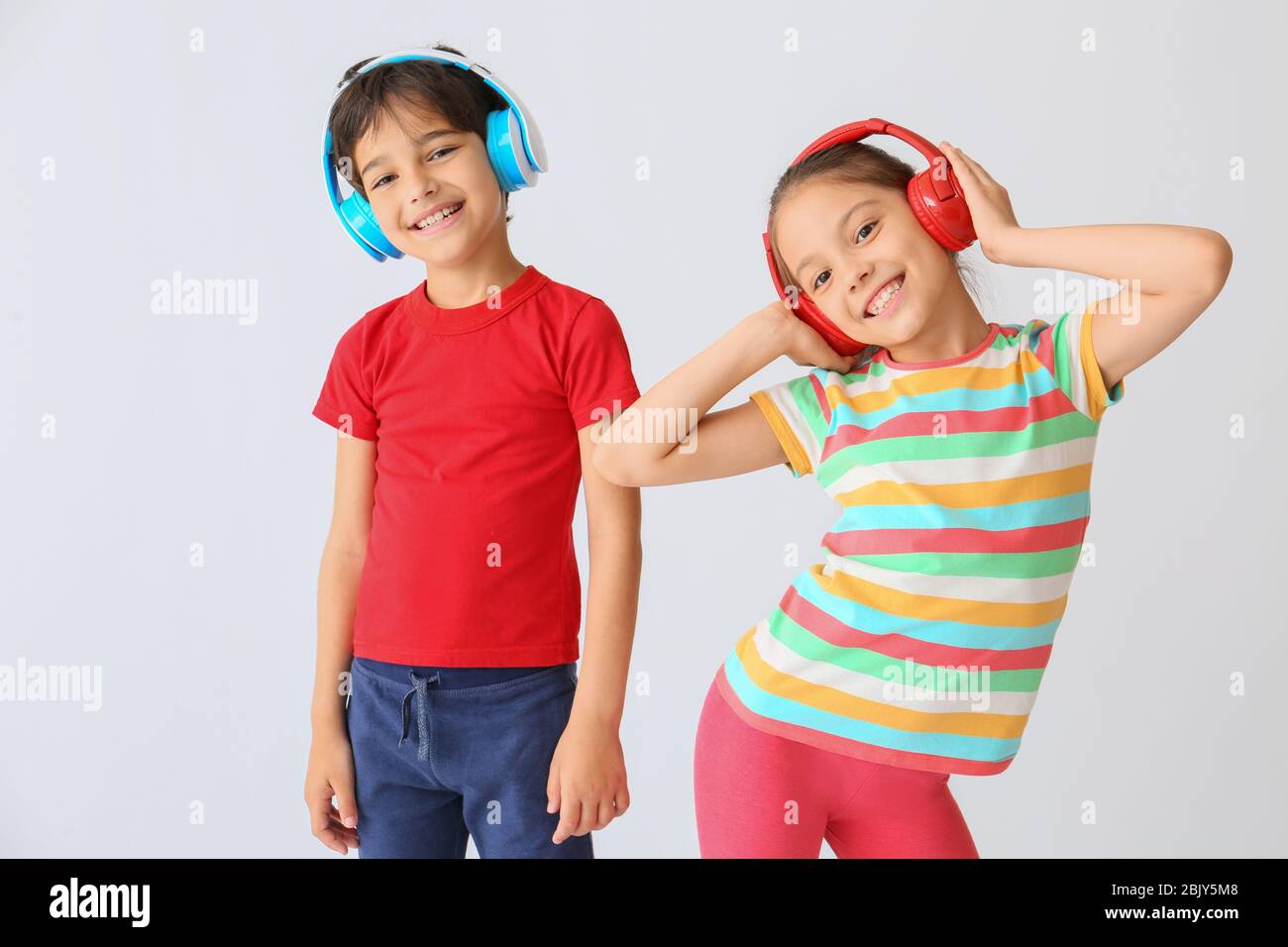 Cute little children listening to music on light background Stock Photo ...