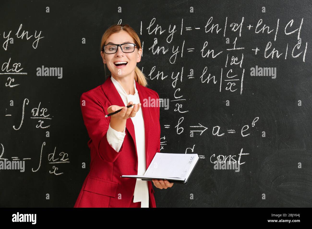 Beautiful math teacher with book near blackboard in classroom Stock ...