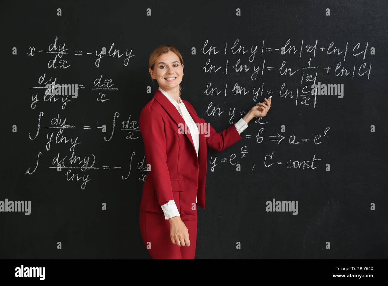 Beautiful math teacher near blackboard in classroom Stock Photo - Alamy