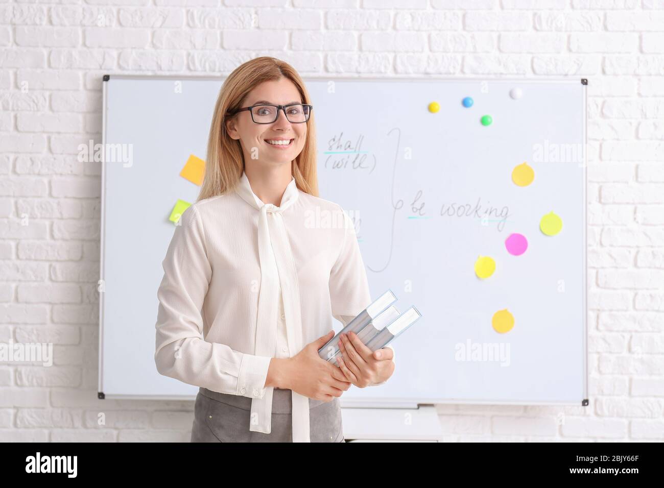 Beautiful English teacher with books in classroom Stock Photo - Alamy