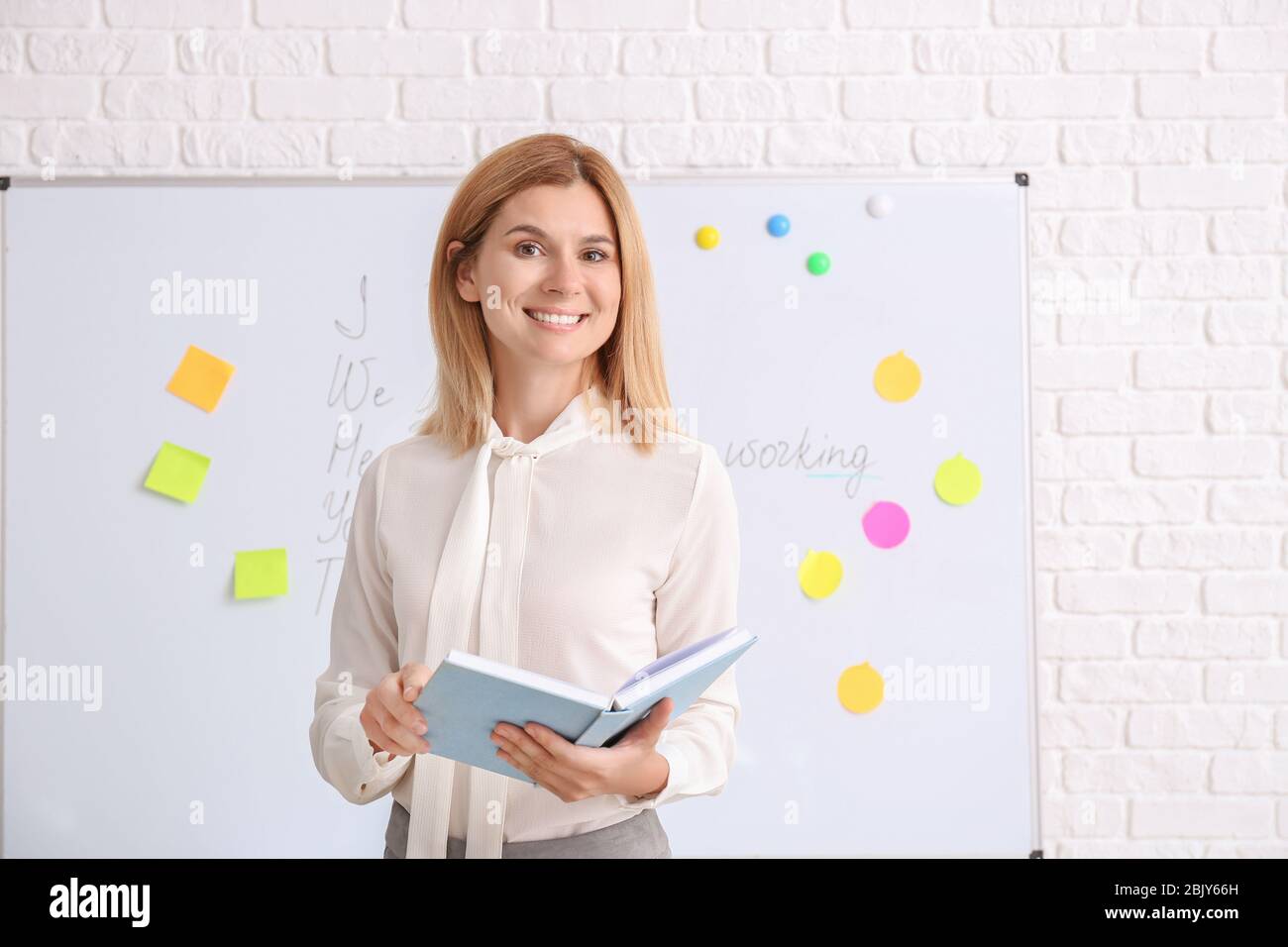 Beautiful English teacher with book in classroom Stock Photo - Alamy