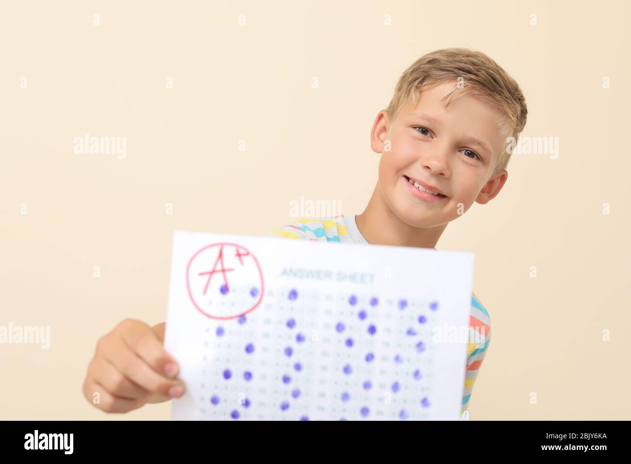 Happy boy with answer sheet for school test on light background Stock ...
