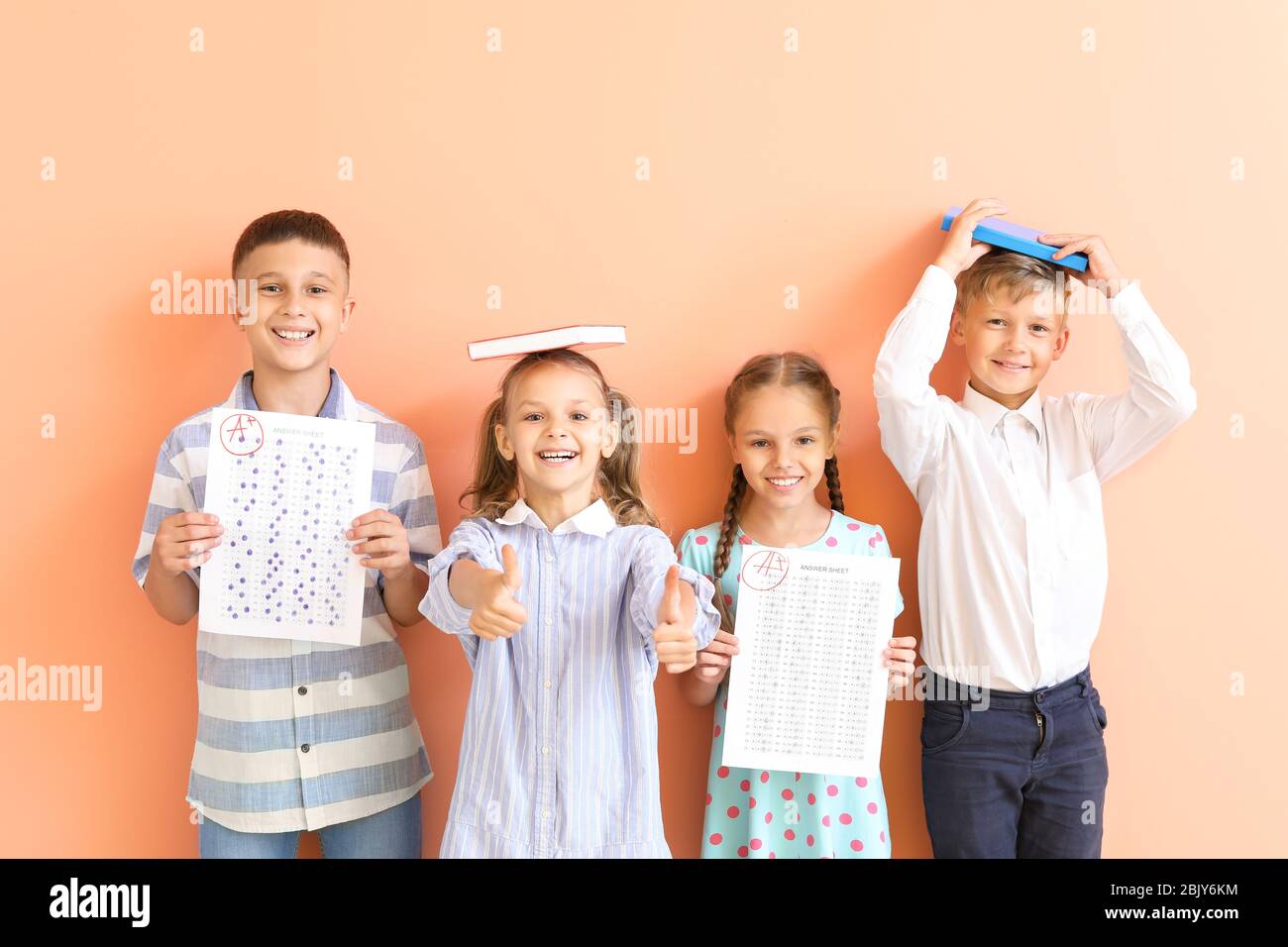 Happy children with answer sheets for school test on color background ...