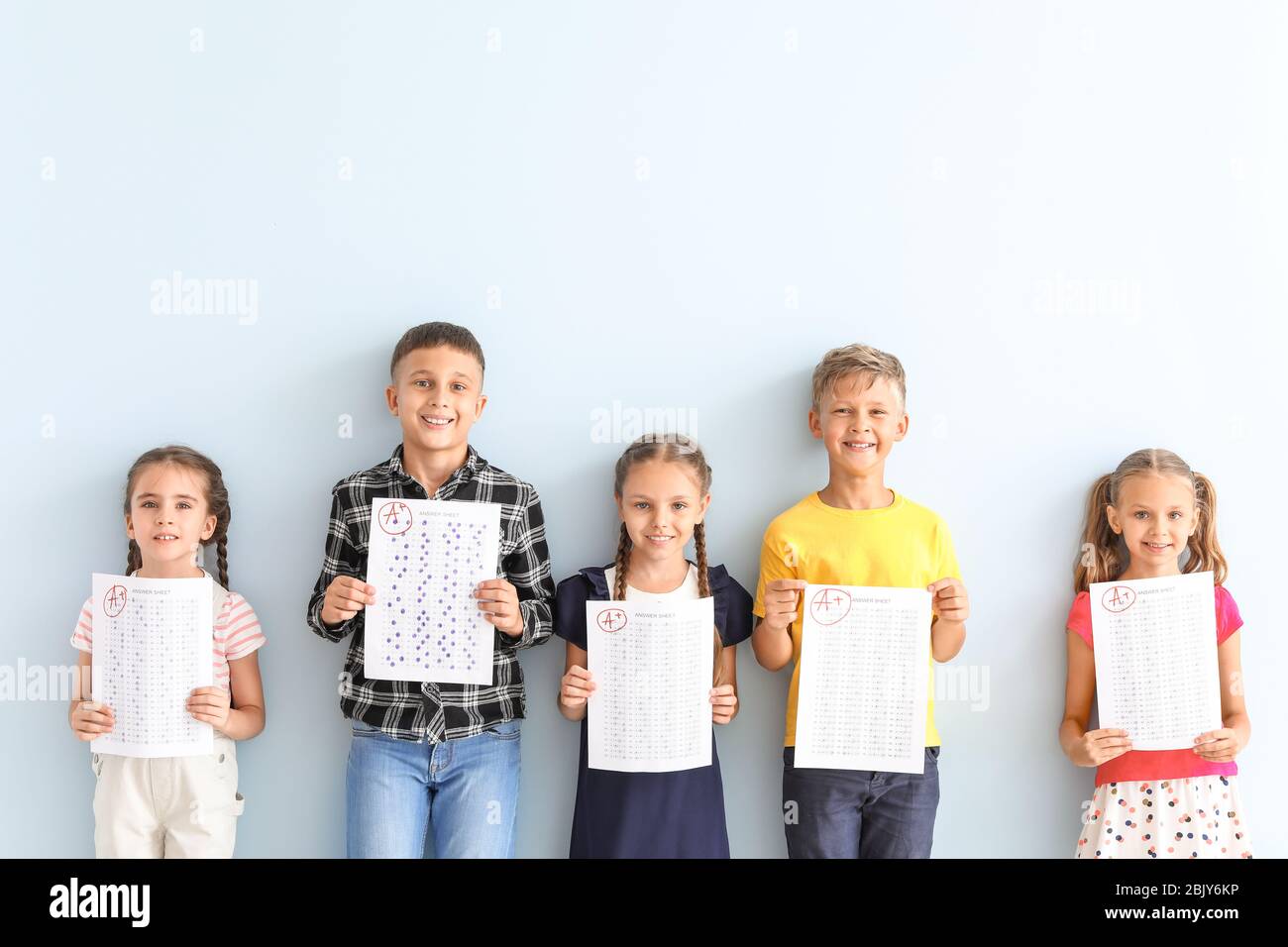 Children with answer sheets for school test on light color background ...