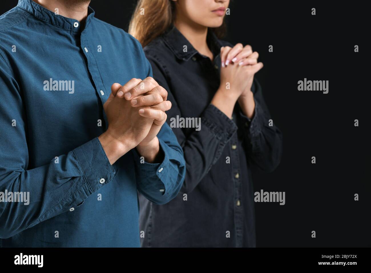 Religious couple praying to God on dark background Stock Photo - Alamy